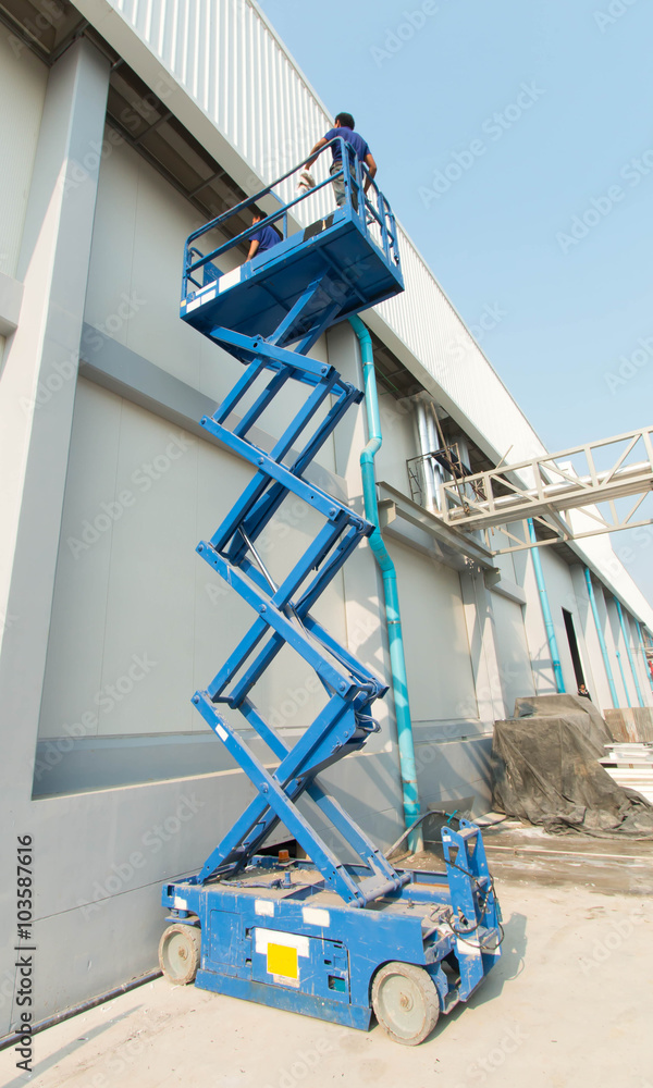 Builder on a Scissor Lift Platform at a construction site. Men at work ...