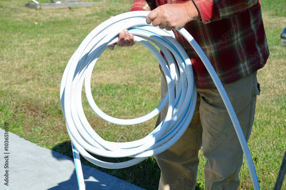 Man rolling the white hose of a camping trailer as he setups his ...