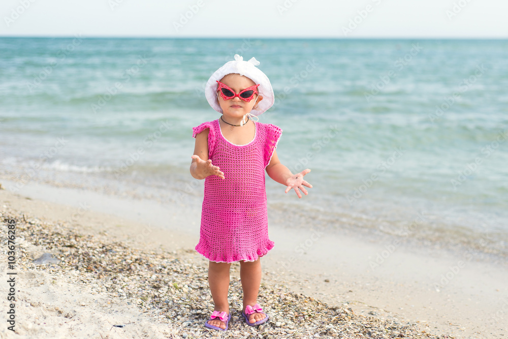 The child, a little girl posing on the beach, small model on the beach ...