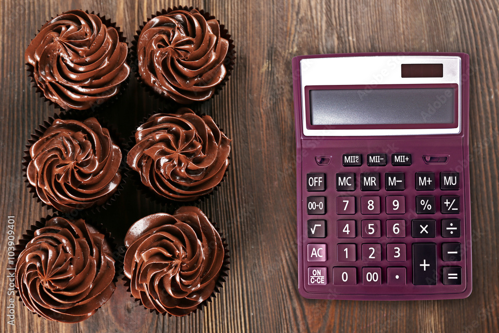Calculator and delicious chocolate cupcakes on wooden background Stock ...