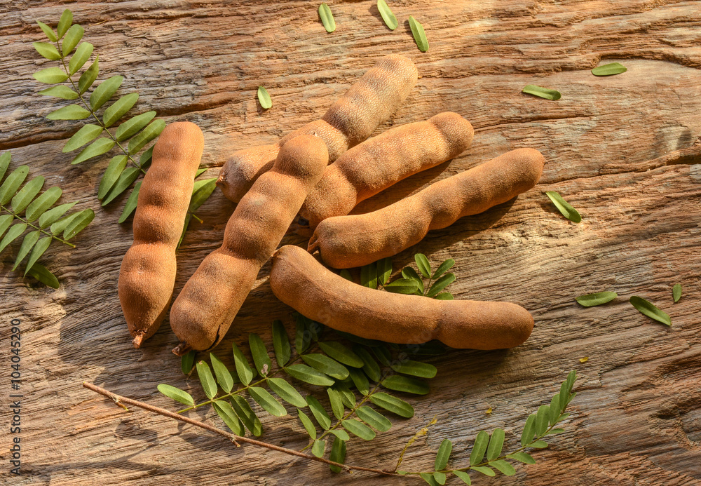 Sweet tamarind pods on wood background, riped is edible as dessert or ...
