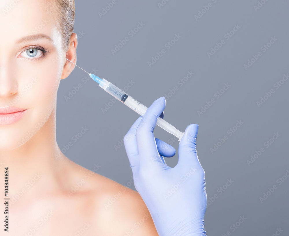Doctor injecting botox in a beautiful face of a young woman. Plastic ...