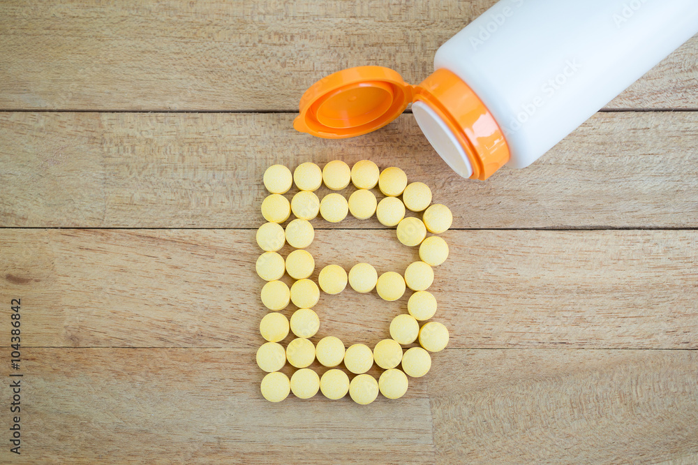 Yellow pills forming shape to B alphabet on wood background Stock Photo ...