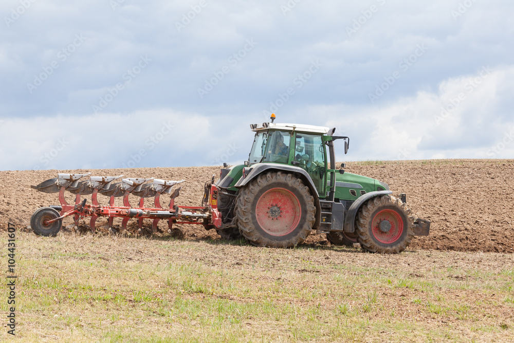 Farmer ploughing an overwintered fallow field with a tractor and plough ...