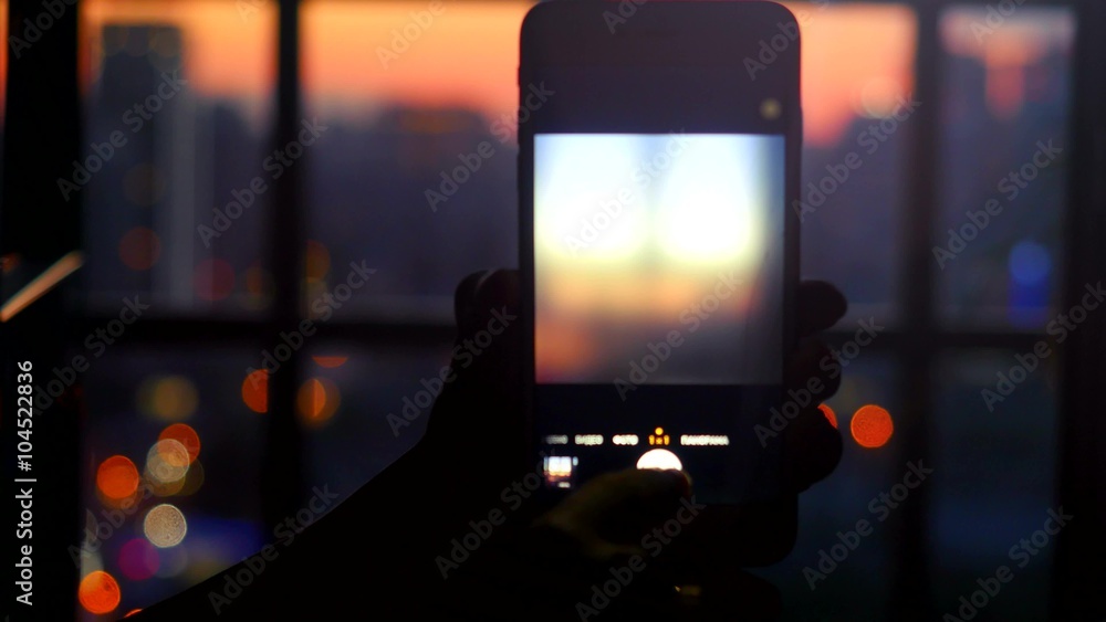 Woman makes a picture from the window with his mobile phone. Night ...