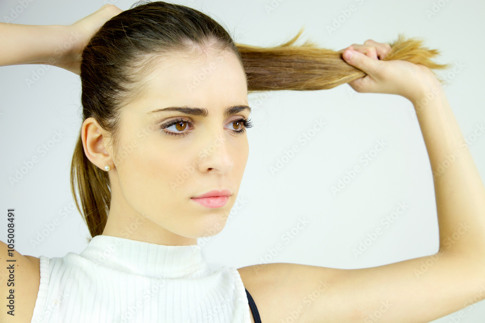Beautiful female model pulling long hair in ponytail looking serious ...