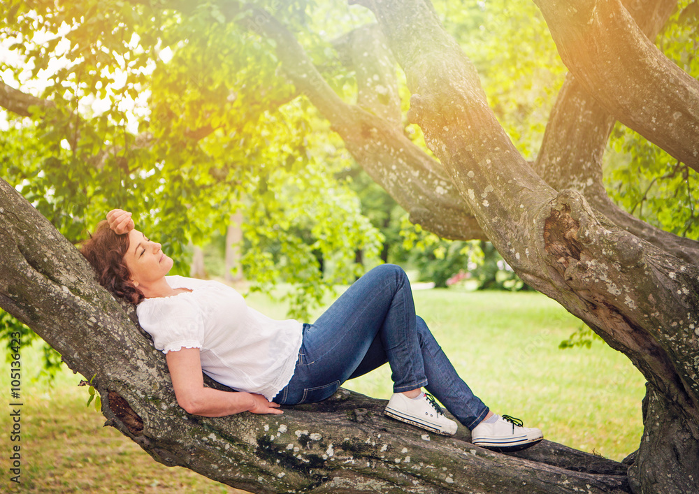 woman relaxing on a big branch of a tree foto de Stock | Adobe Stock