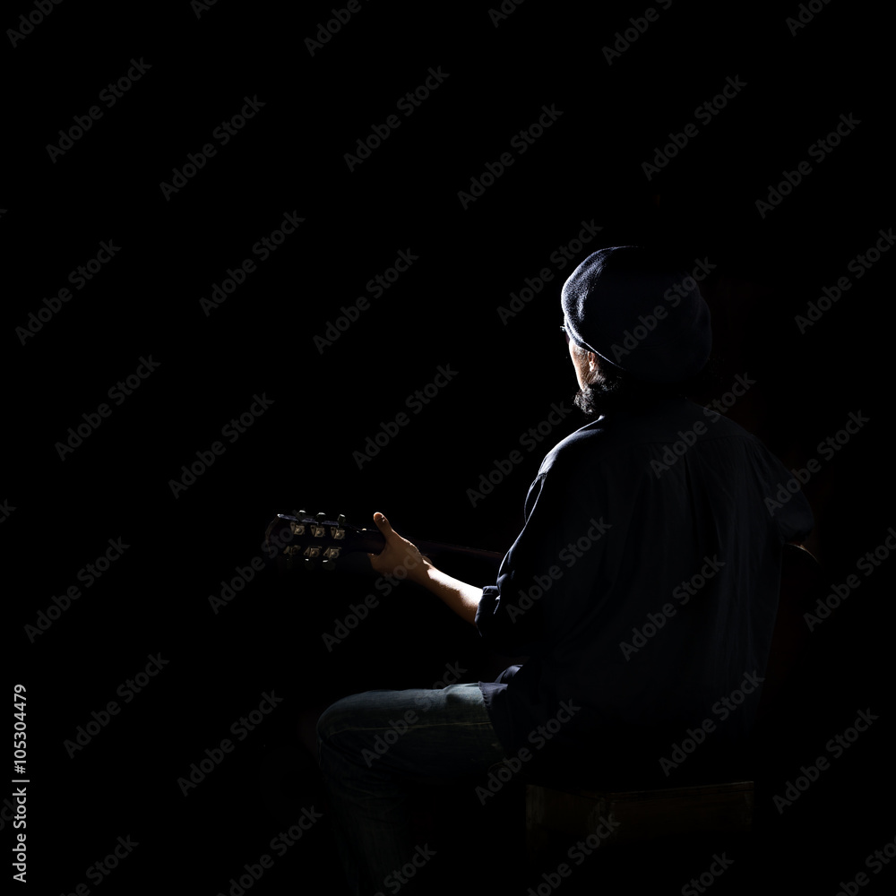 Man playing guitar in studio play of light and shadow on black ...