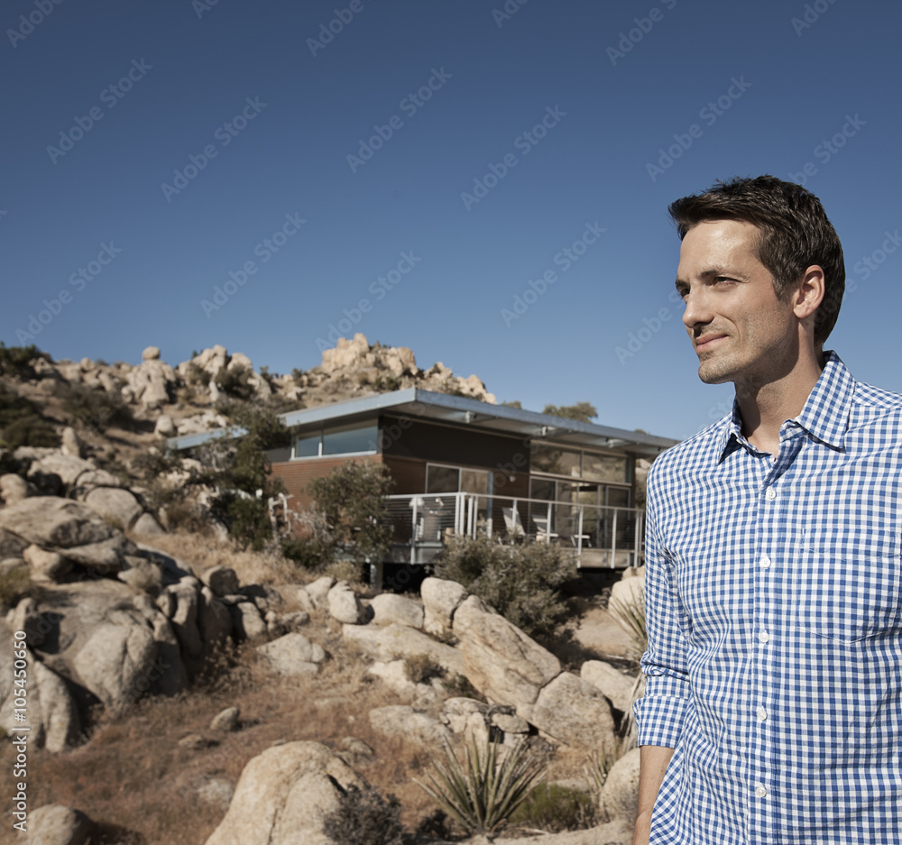 A man standing in front of an eco home, designed to blend into the ...