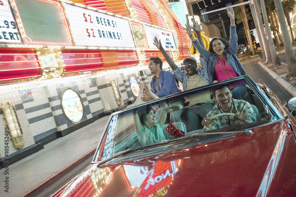 A group of friends in a red open top convertible classic car ...