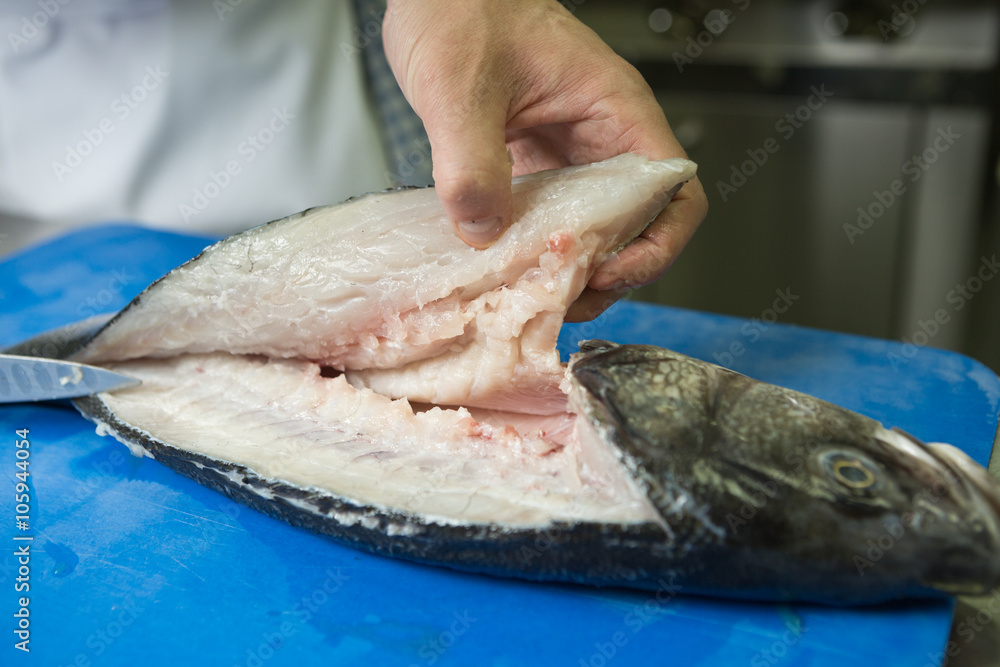 Filleting and removing the bone from a fresh fish on a blue cutting ...