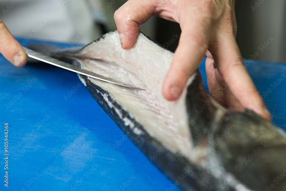 Filleting and removing the bone from a fresh fish on a blue cutting ...