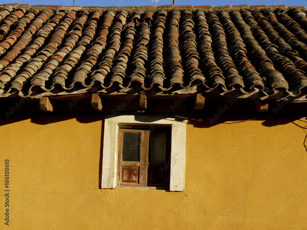 Tejado y ventanuco de una casa amarilla Stock Photo | Adobe Stock