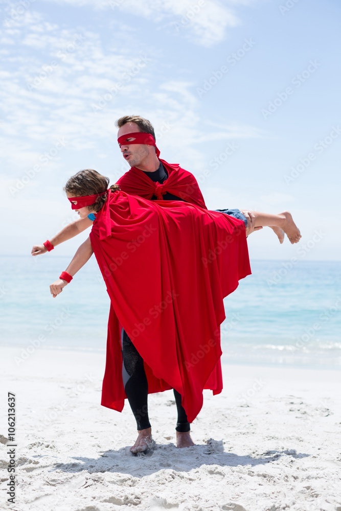 Fotografia do Stock: Father in superhero costume lifting son at sea ...