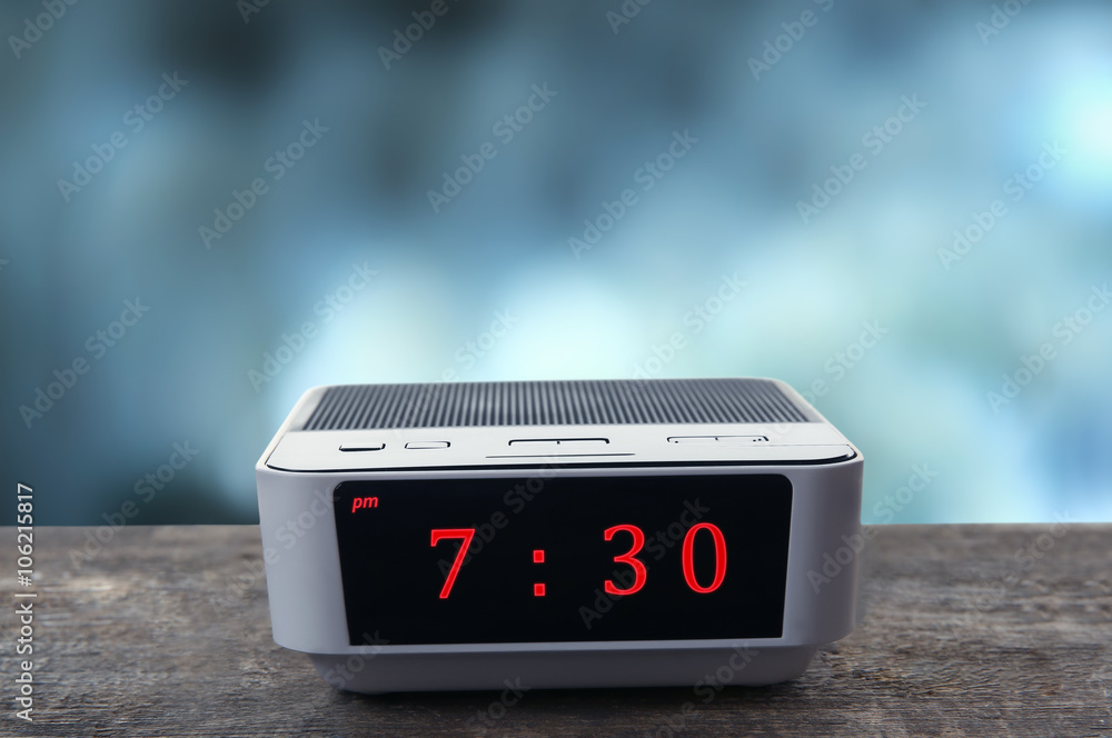 Digital clock showing 7:30 o'clock on wooden table, night background ...