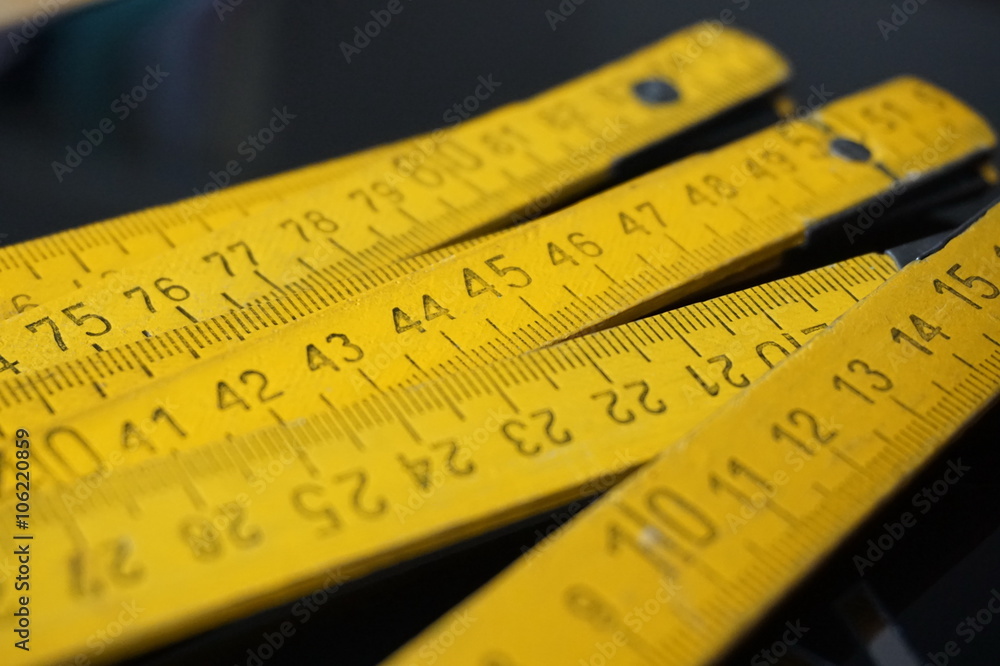 Old yellow folding meter ruler measuring centimeters on the black ...