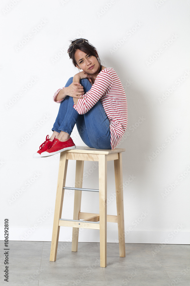student vacation smile - playful young ethnic girl sitting on a stool ...