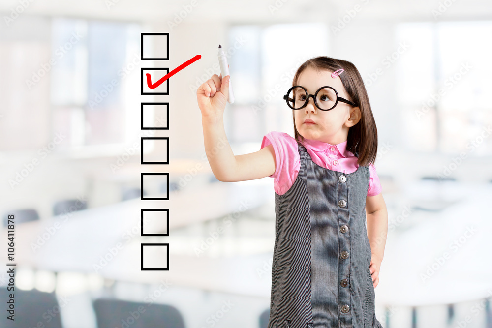 Cute little girl wearing business dress and checking on checklist box ...