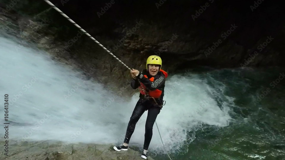 outdoor adventurer rappelling large water volume waterfall shot from ...