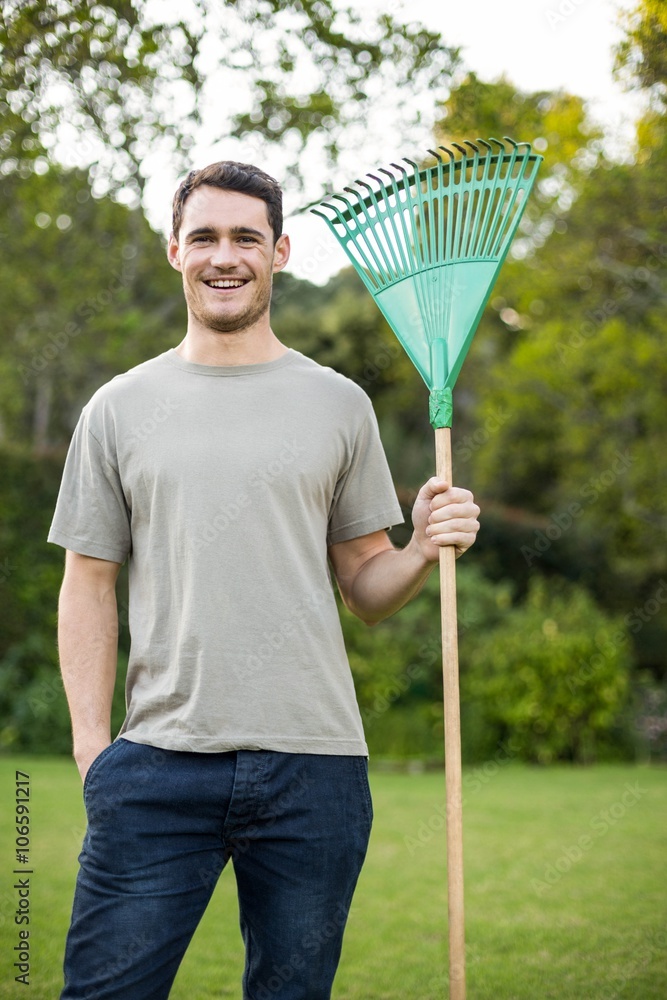 Portrait of young man standing with a gardening rake Stock Photo ...