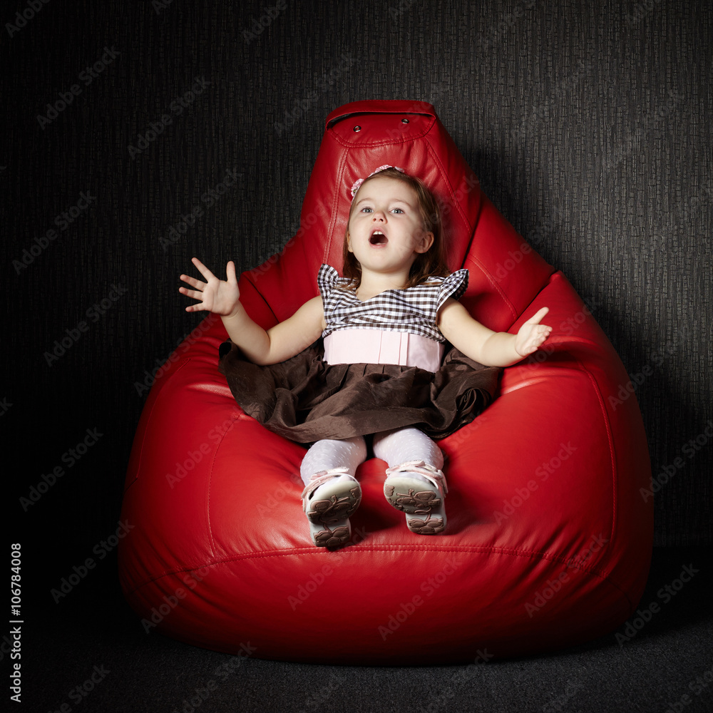 Little girl sitting on red beanbag Stock Photo | Adobe Stock