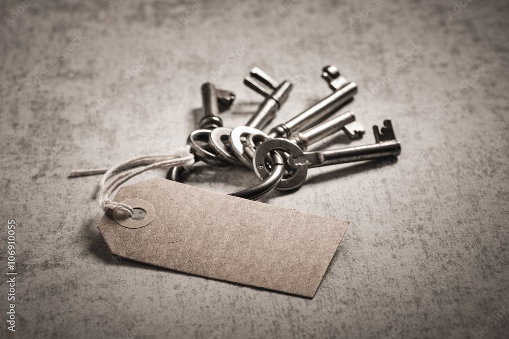 Vintage key set with blank paper tag on stone table. Symbol of ...