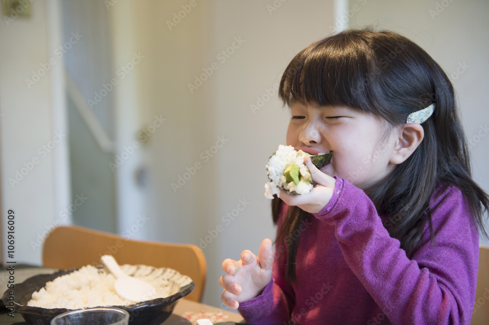Girl eating large rice parcel at dining table Stock Photo | Adobe Stock
