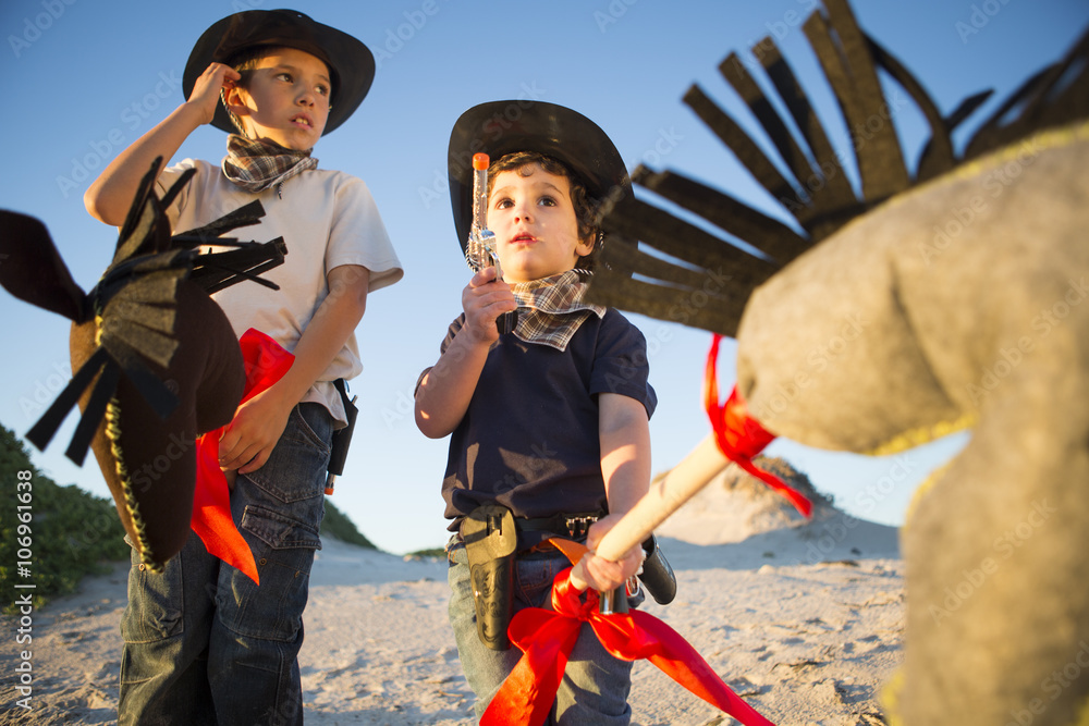 Two brothers dressed as cowboys with toy gun and hobby horse's Stock ...