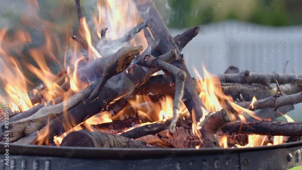 Flames rising up from burning pile of sticks a fire pit in a back yard ...