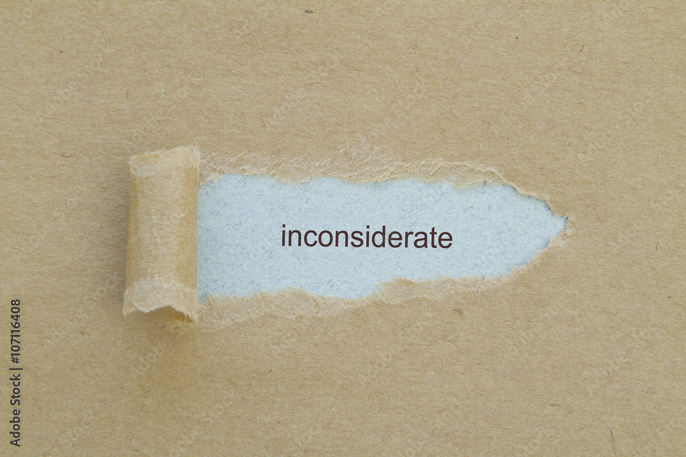 inconsiderate word written under torn paper. Stock Photo | Adobe Stock