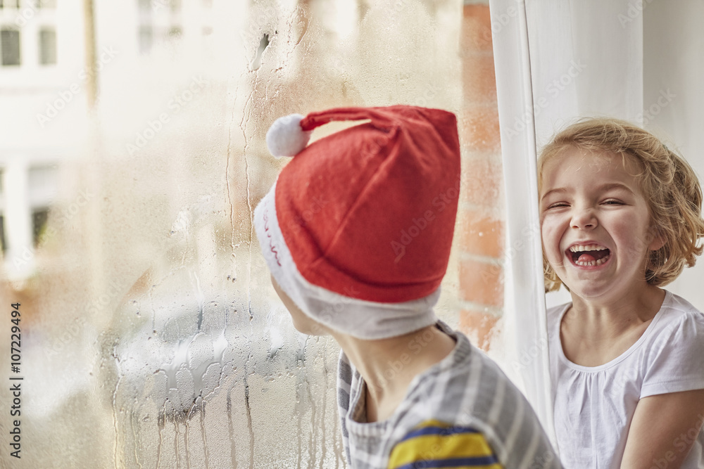 Christmas morning in a family home. A boy in a Santa hat looking out of ...