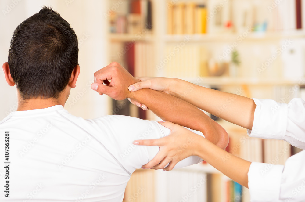 Female physio therapist and man seen from behind, helping patient ...