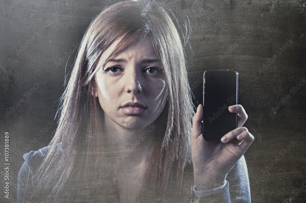 worried teenager holding mobile phone as internet cyber bullying ...