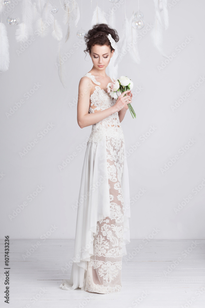 Tall and slim young bride in a luxurious lace wedding dress. She has a ...