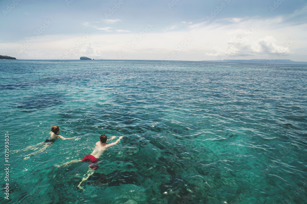Romantic couple swimming in blue water of Indian ocean holding hands ...