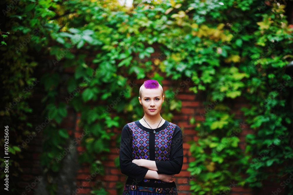 Beautiful punk girl with a purple mohawk standing against a background ...