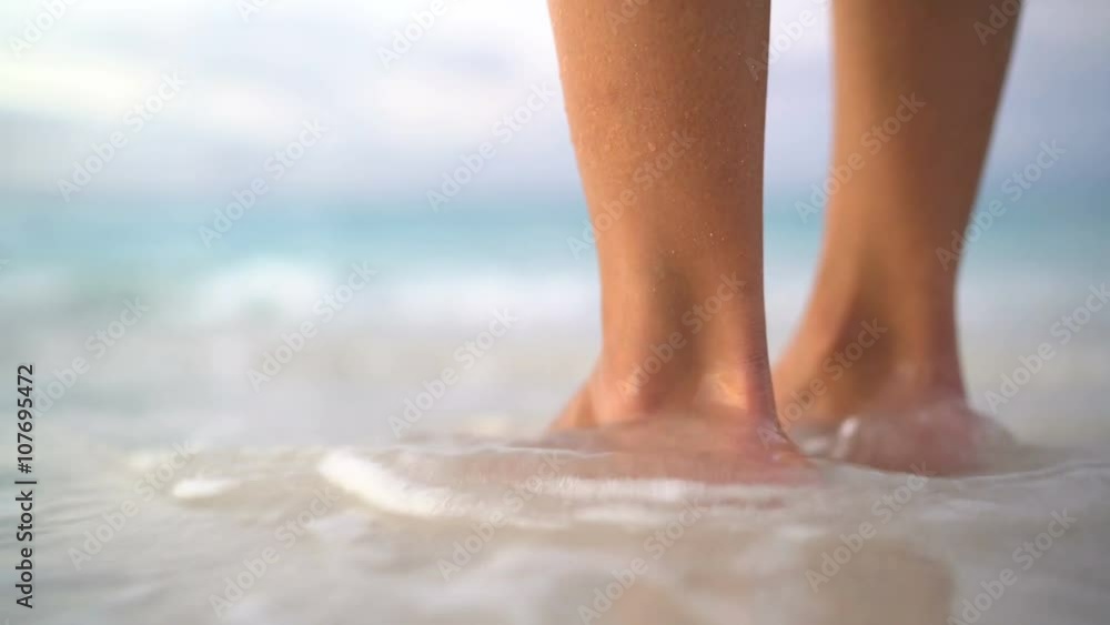 Close up of woman feet on beach. Girl getting her toes wet on vacation ...