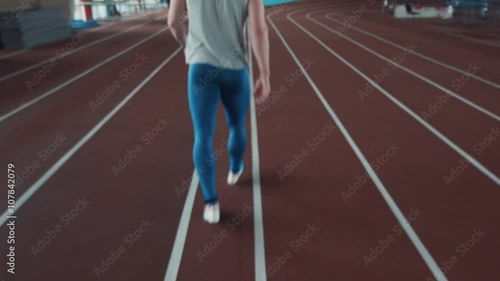 The tired sprinter the athlete breathe and goes on a running track ...