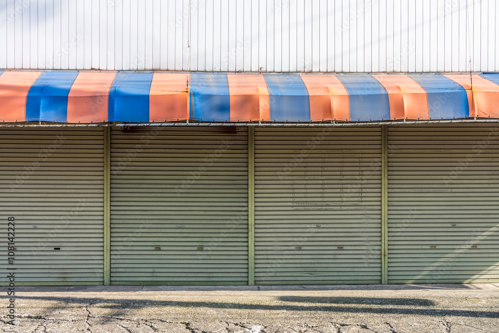 The facade of closed retail store. There are awning and rolling steel ...