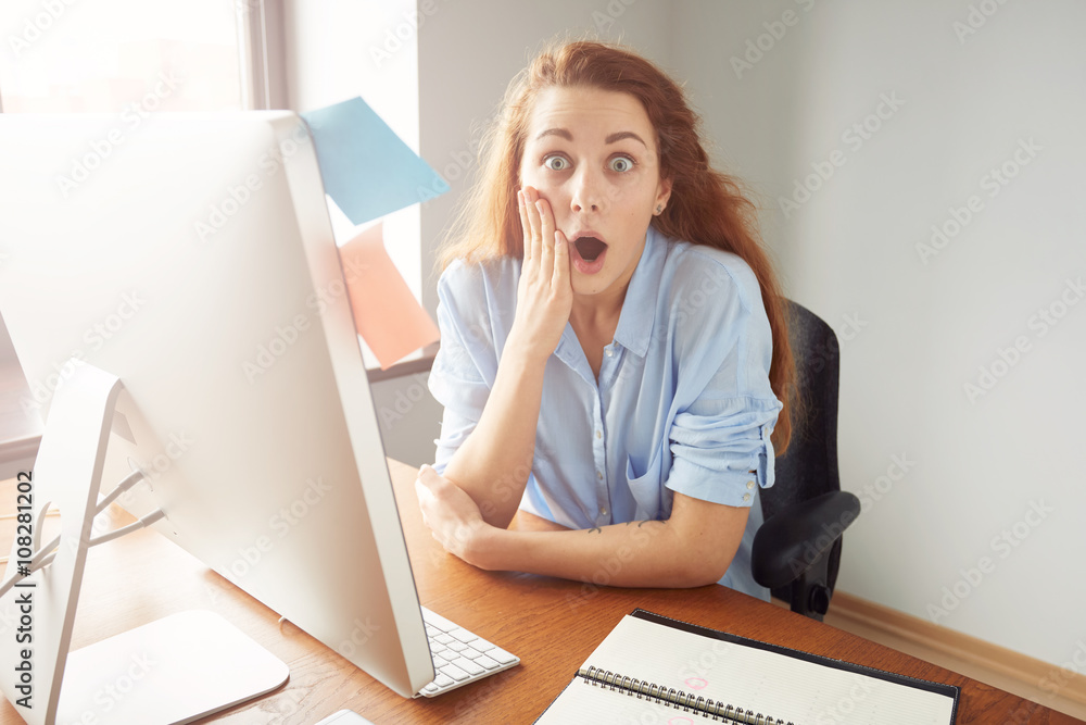 Young female office worker looking surprised and shocked at the camera ...