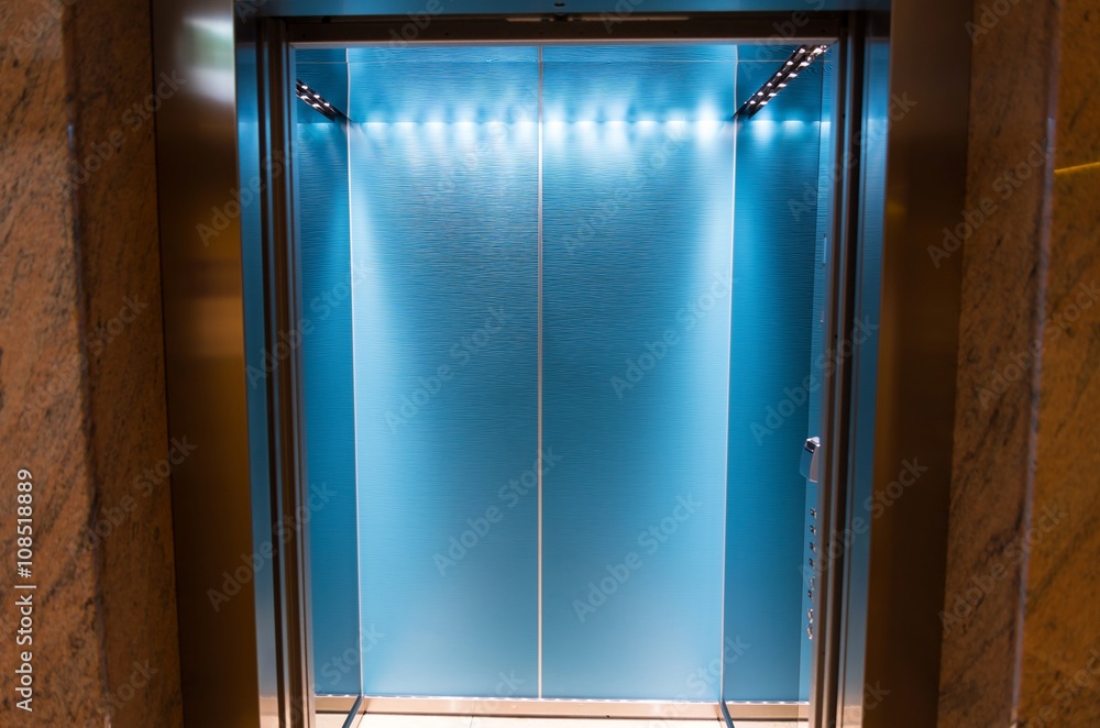 An empty modern blue elevator or lift with metal doors that are open in ...