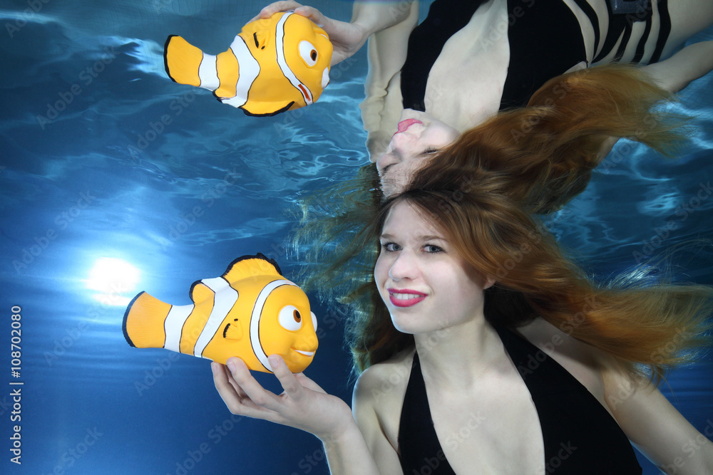 Beautiful woman with Nemo fish and swimsuit underwater in the pool ...