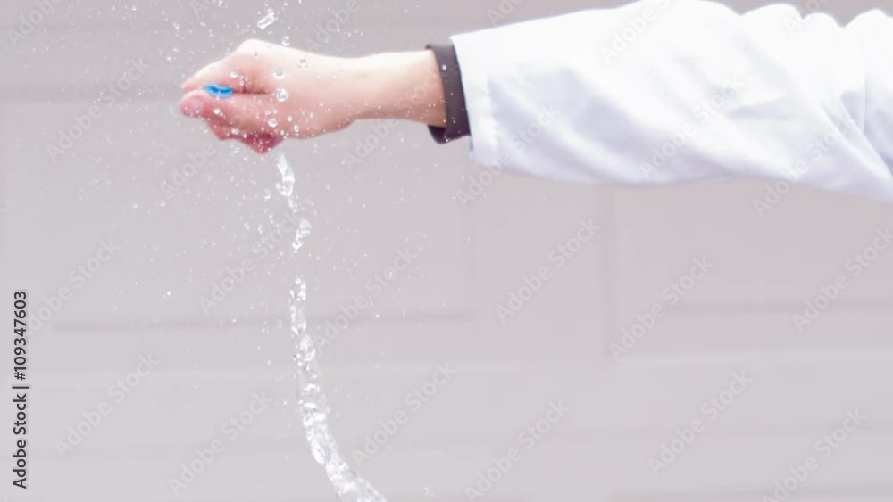 Scientist holding water balloon, pricking it with a pin to make it pop ...