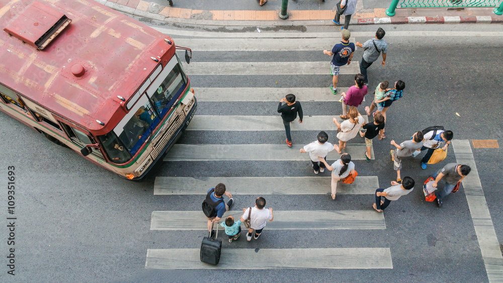 People are walking across road before the bus is going to stop at the ...
