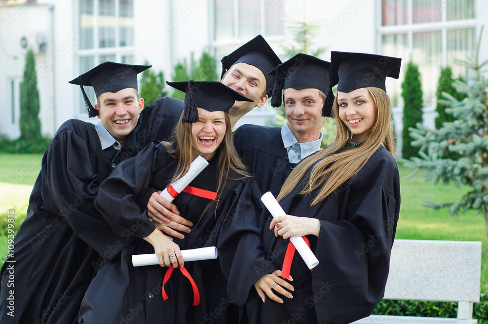 Graduates embrace, enjoy and look at the camera on the graduation ...