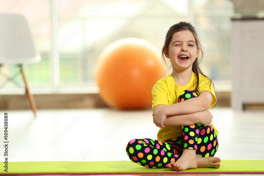Little funny girl sitting on a mat indoor Stock Photo | Adobe Stock
