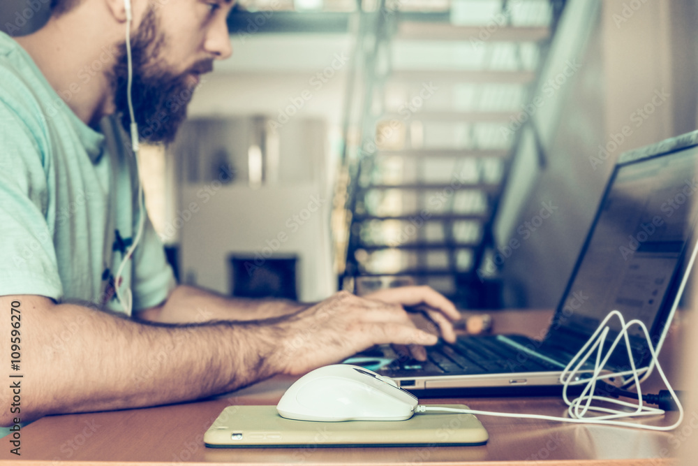 man with a beard is working at the computer, on the background of two ...
