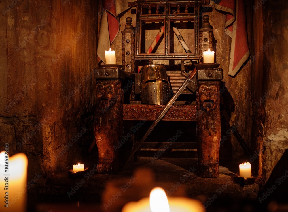 Medieval royal throne with helmet and sword in ancient castle interior ...