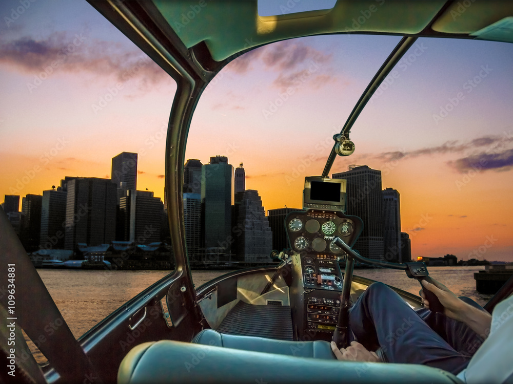 Helicopter cockpit on New York skyline at sunset, with pilot arm and ...