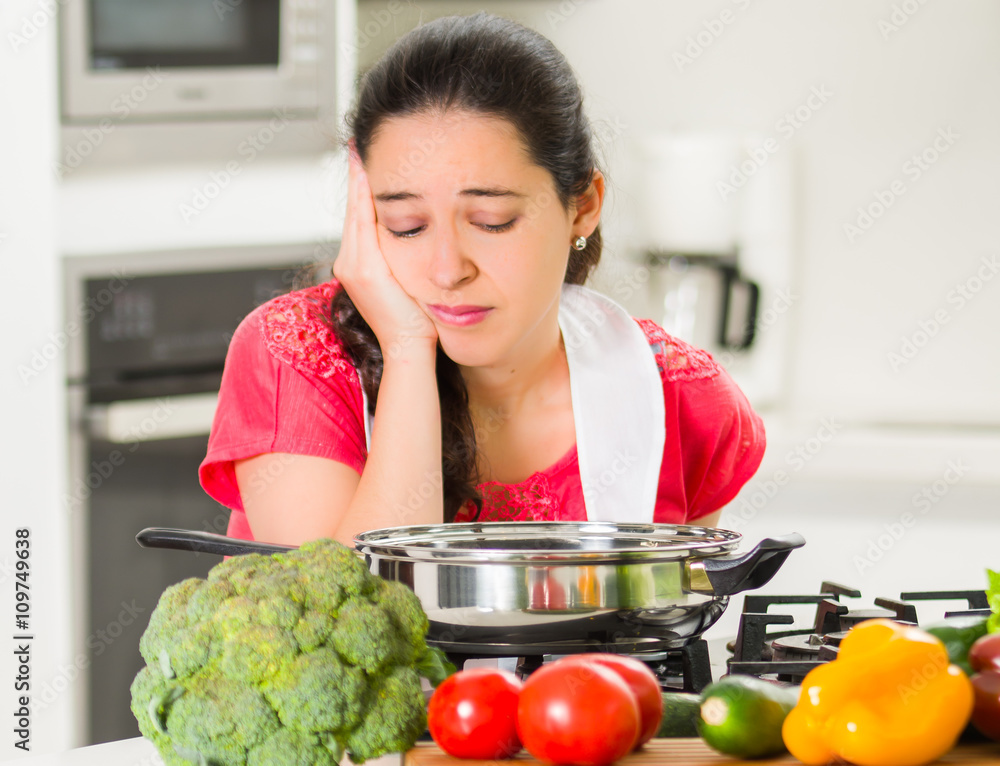 Young woman chef cooking with skeptical facial expressions, interacting ...
